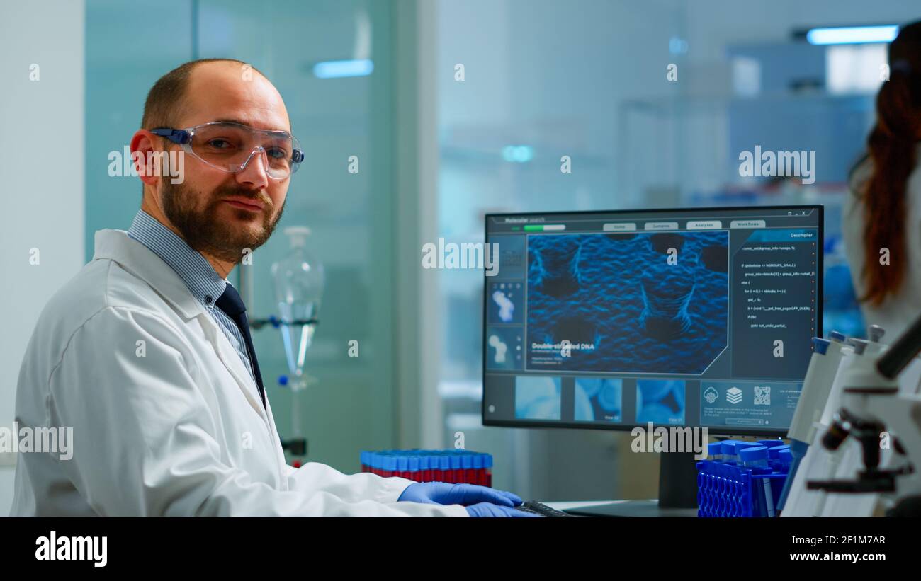 Portrait of scientist man looking at camera sitting in modern equipped ...