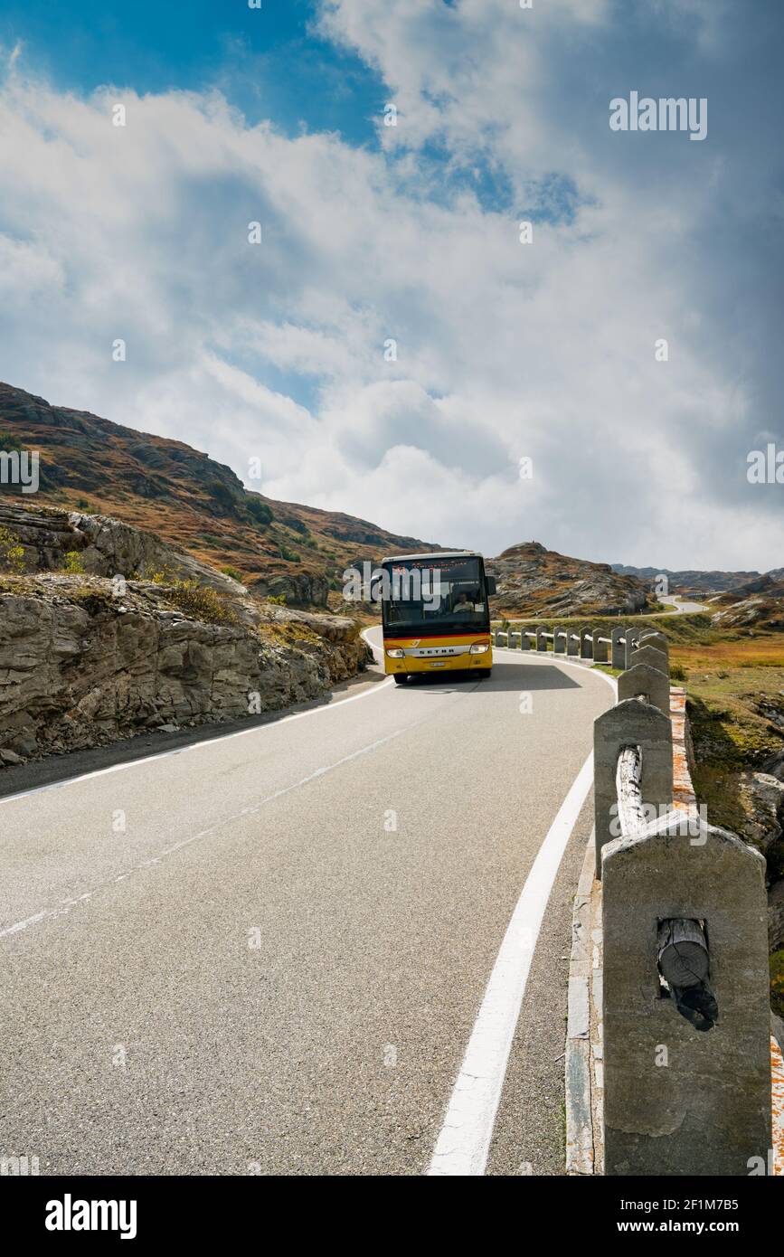 Swiss post bus on a two-lane road leading over a high remote and wild ...