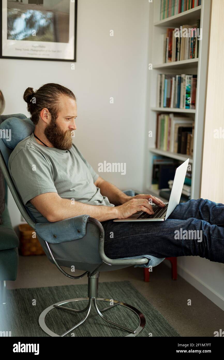 Man sitting on chair and using laptop Stock Photo - Alamy
