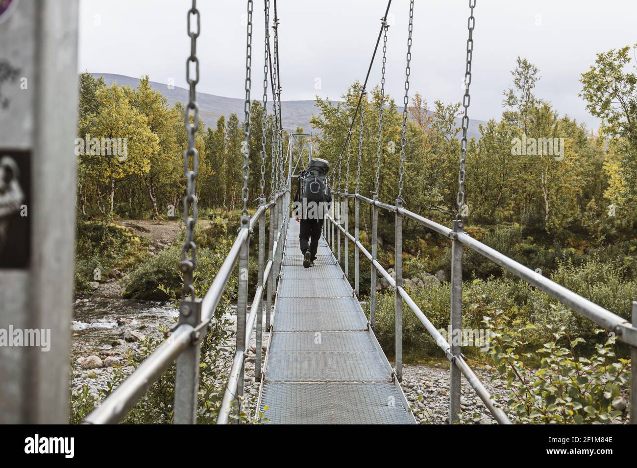 Rear view of hiker crossing hanging bridge Stock Photo - Alamy