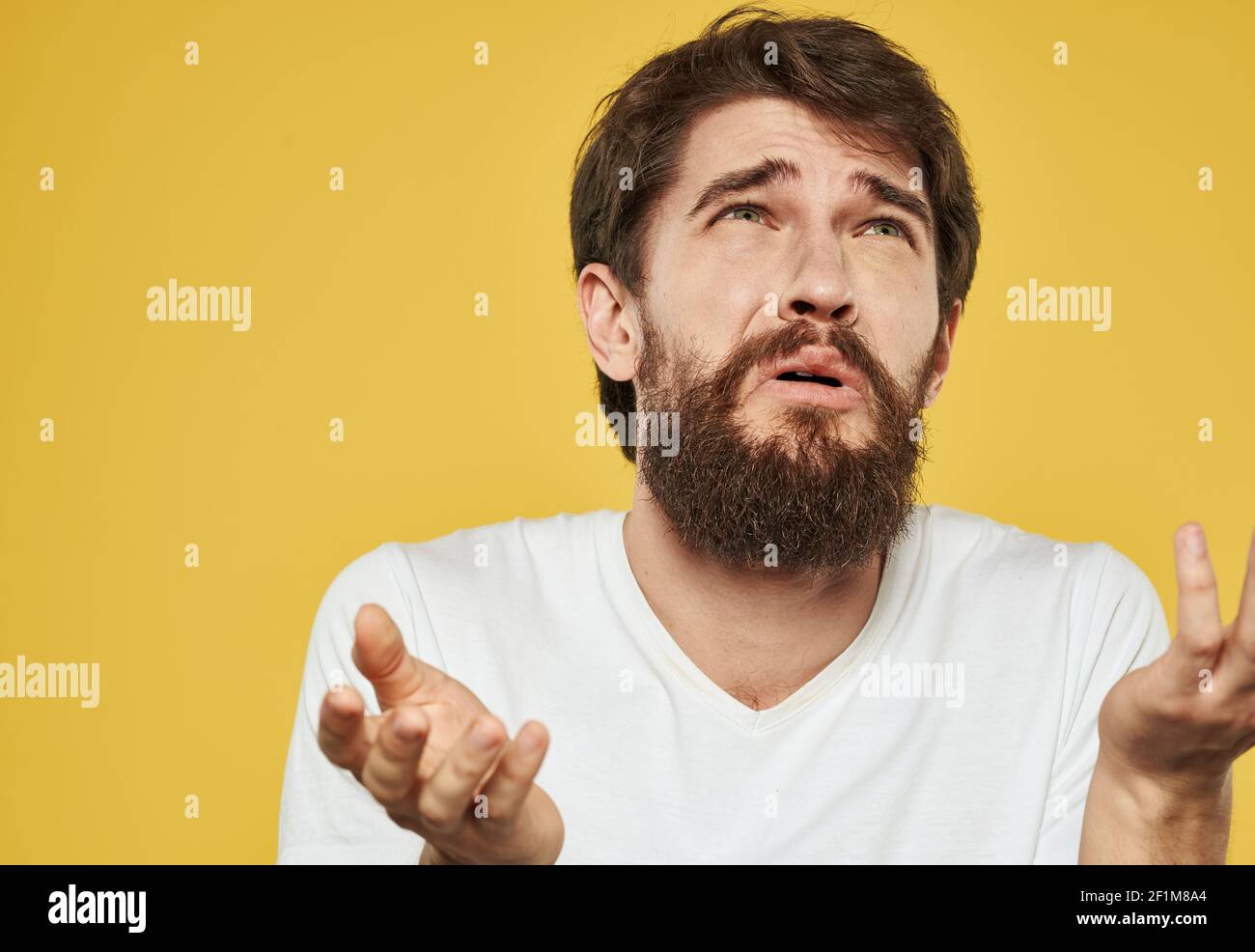 Upset guy crying on a yellow background and gesturing with his hands ...