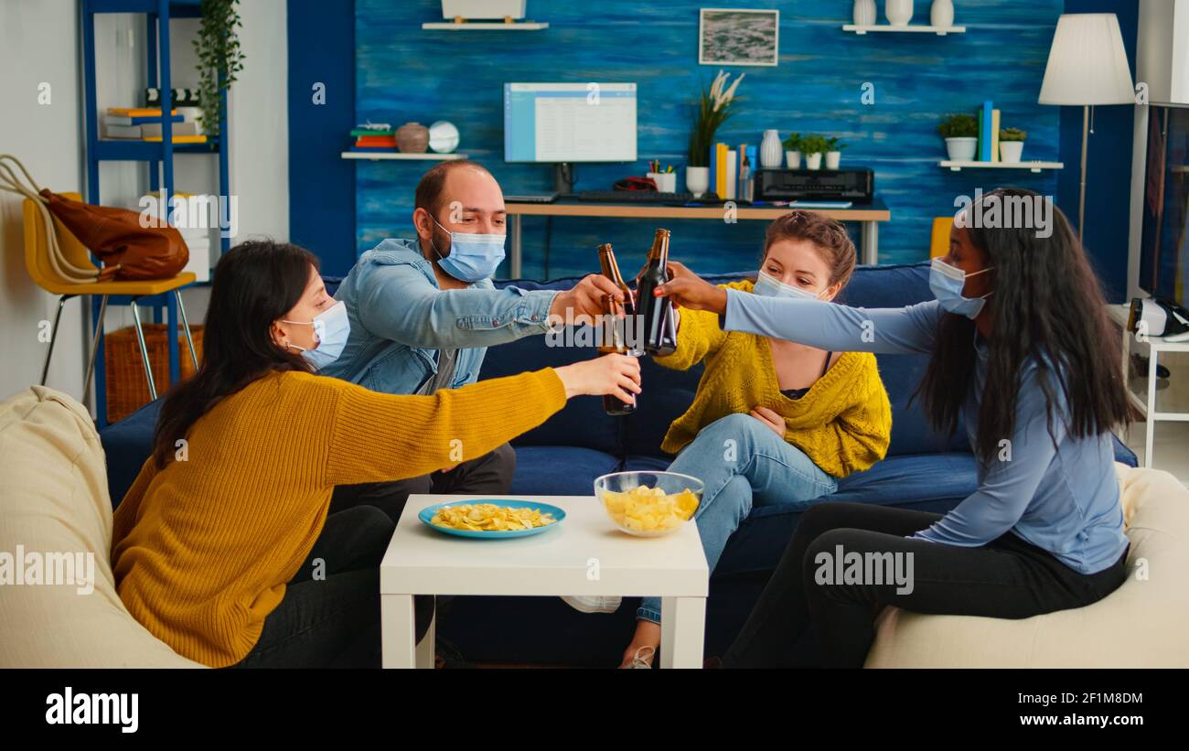 Mixed race friends clinking beer bottles hanging out keeping social ...