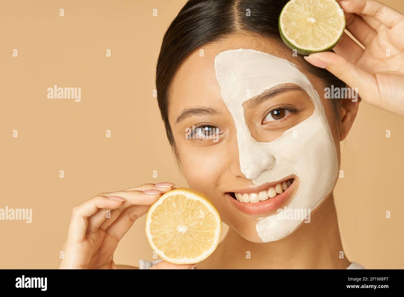 Beauty portrait of young woman with facial mask applied on half of her ...