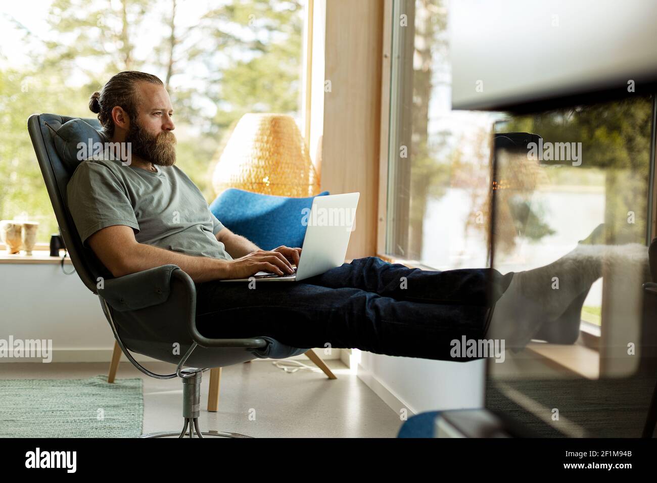 Man sitting on chair and using laptop Stock Photo - Alamy