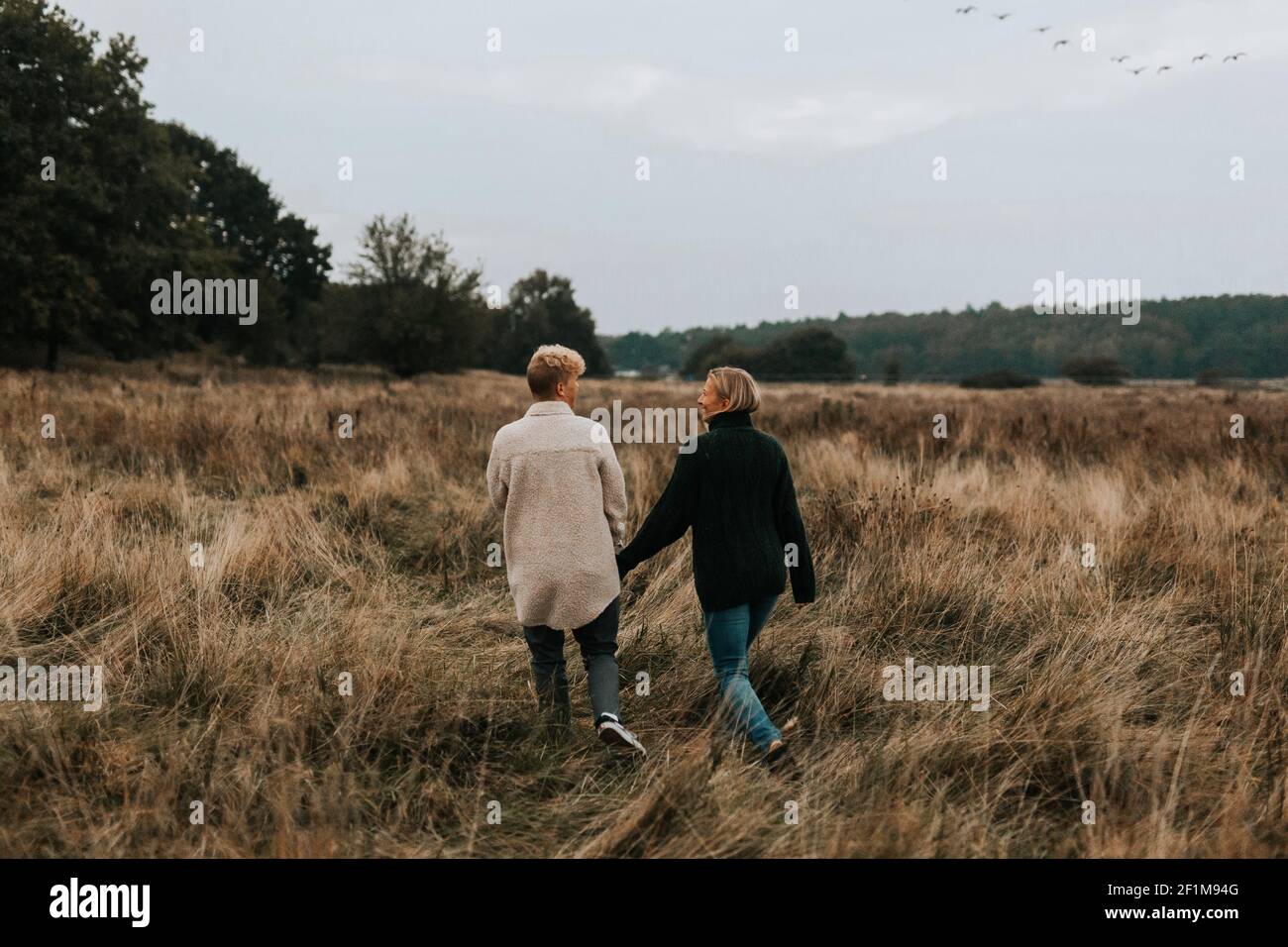 Female couple walking through meadow Stock Photo - Alamy