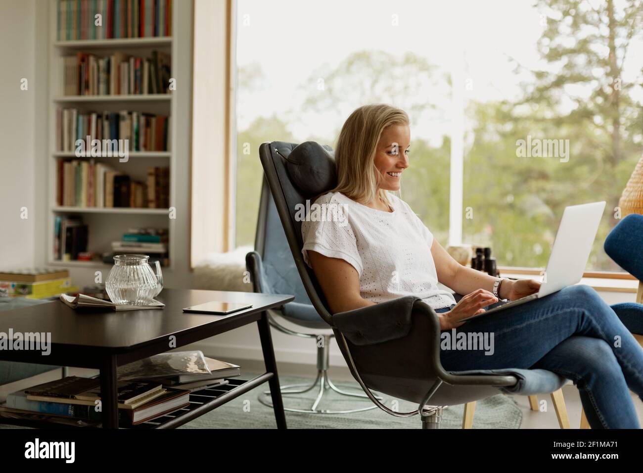 Woman sitting in living room and using laptop Stock Photo - Alamy