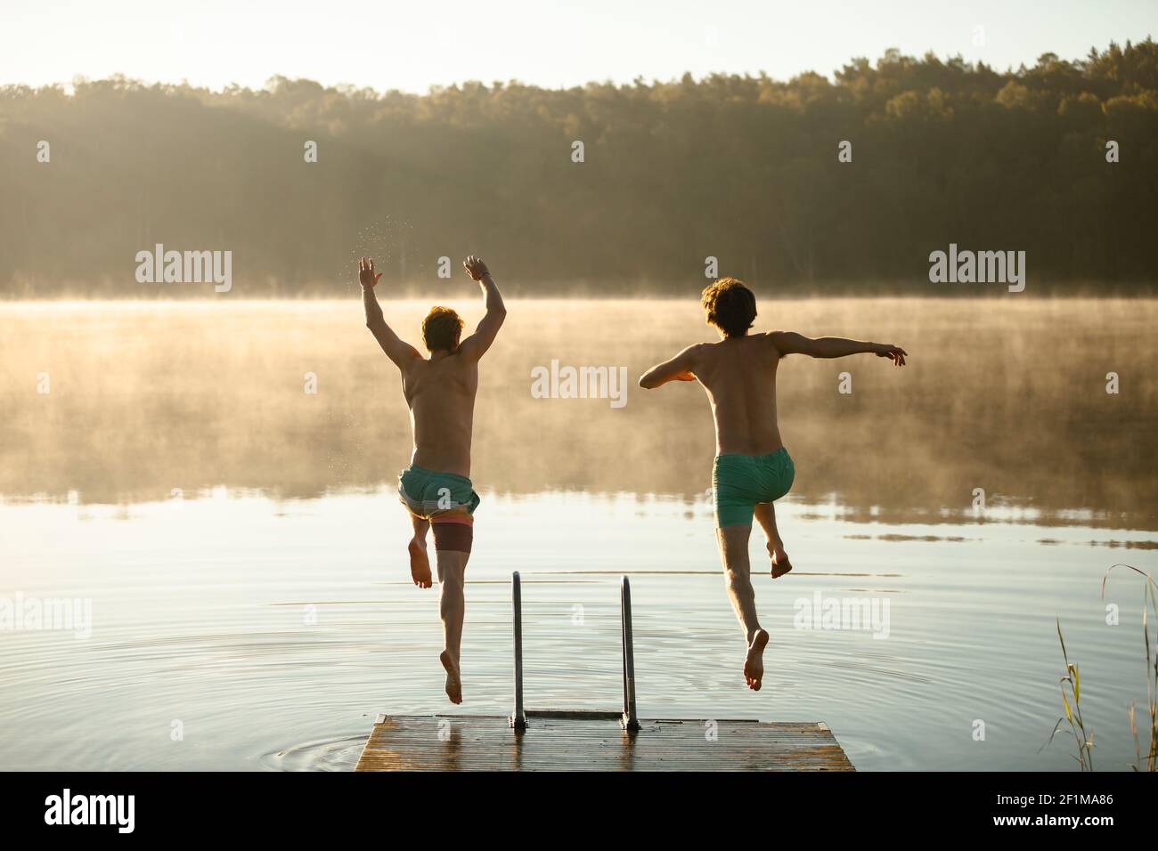 Men jumping into lake Stock Photo - Alamy