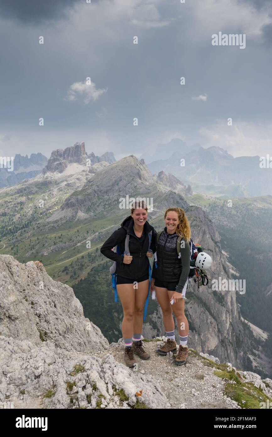 Two attractive young mountain climbers standing on a mountain peak and ...