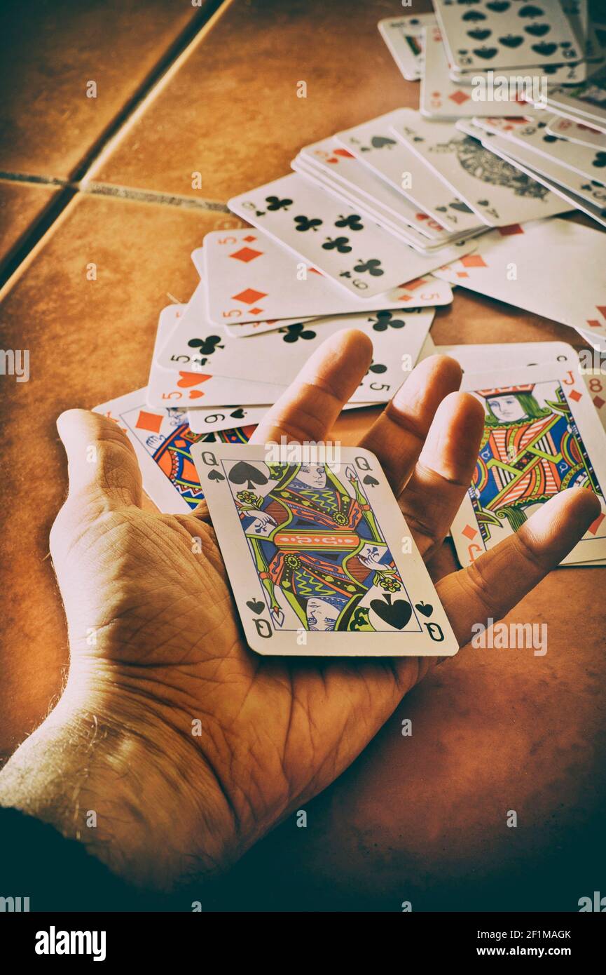 man hand lying on the floor with playing cards spread around Stock ...
