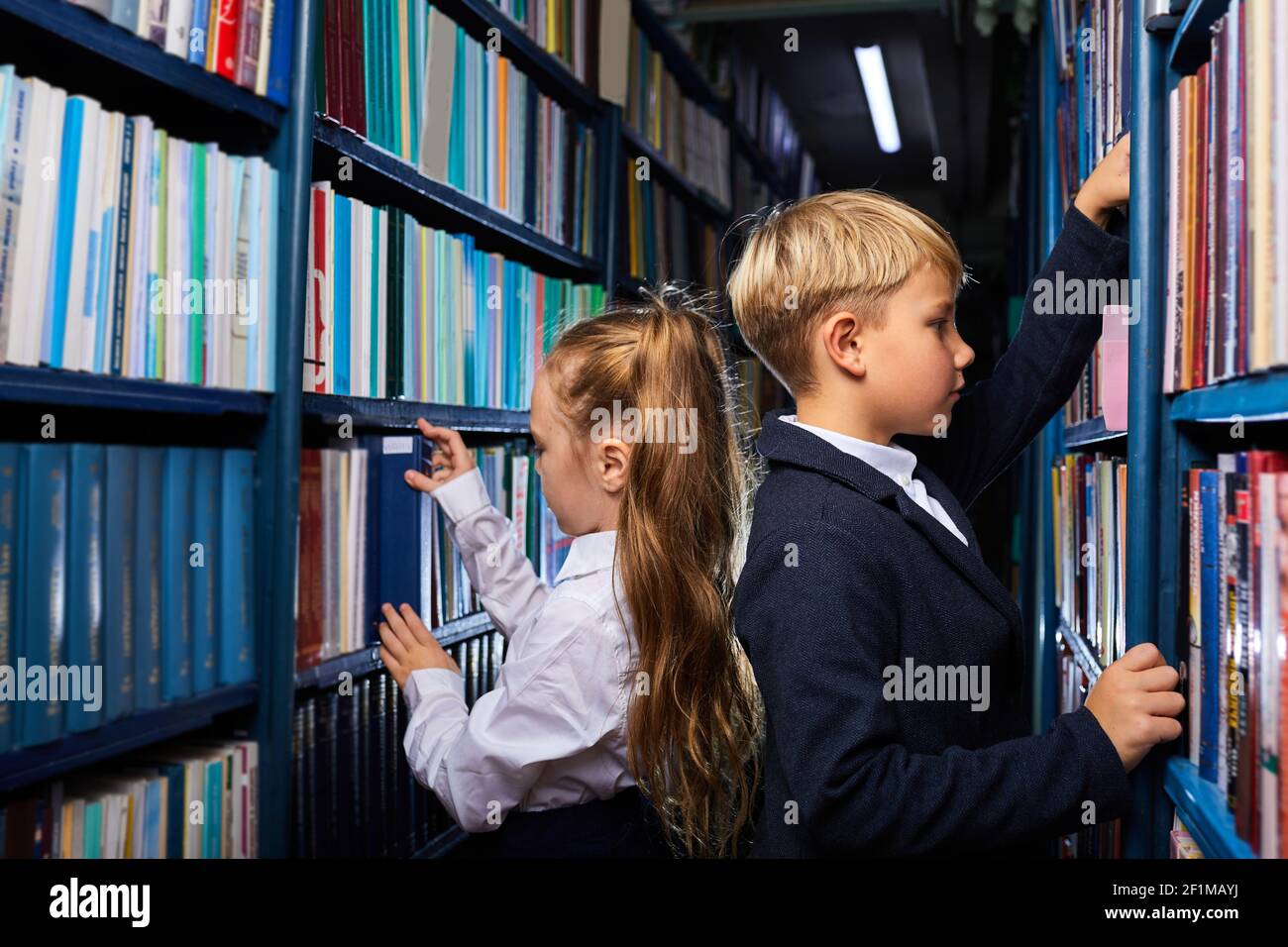 kids boy and girl choose books in library for school, going to read ...