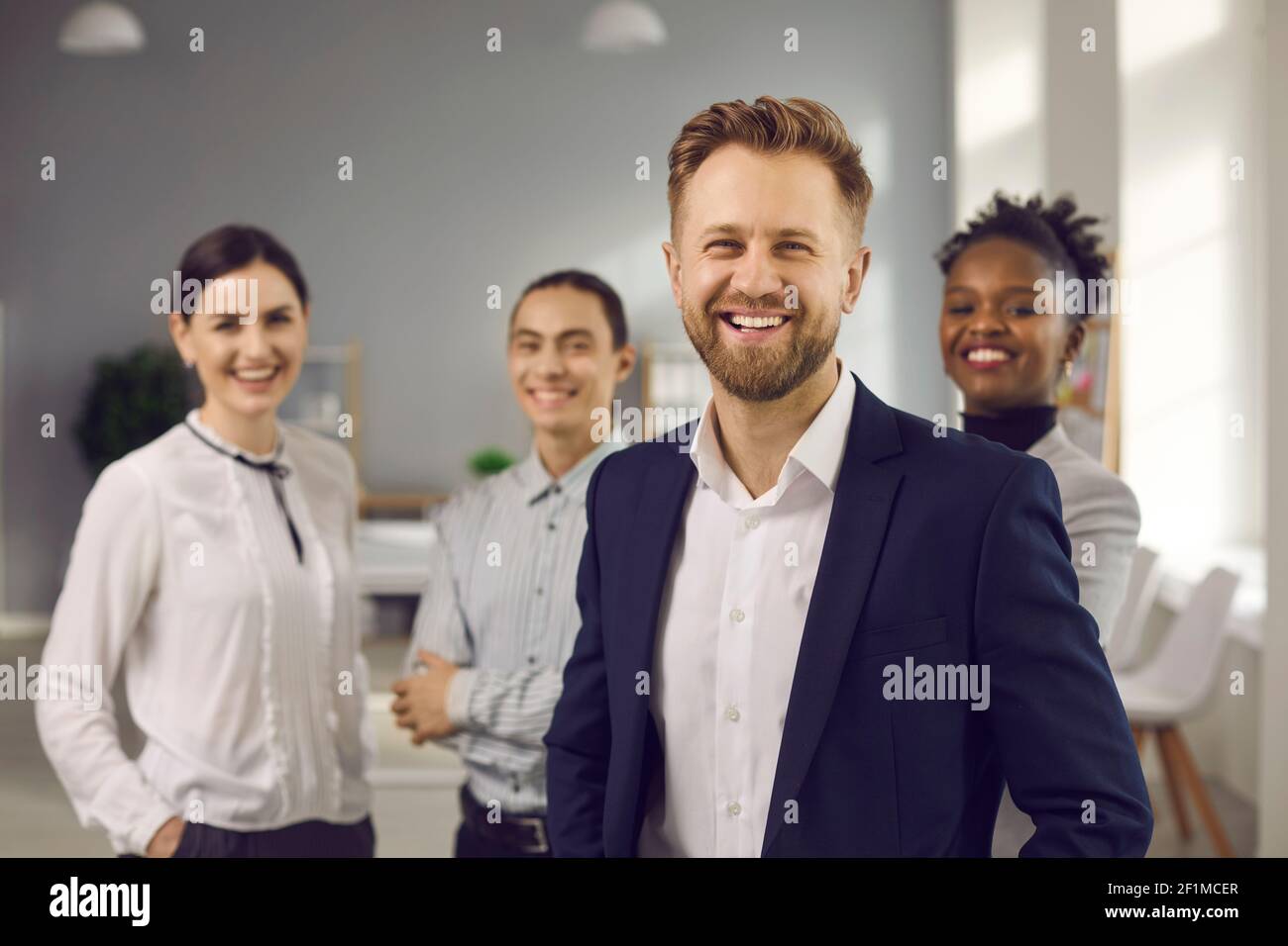 Happy startup CEO with team of employees standing in office and smiling ...