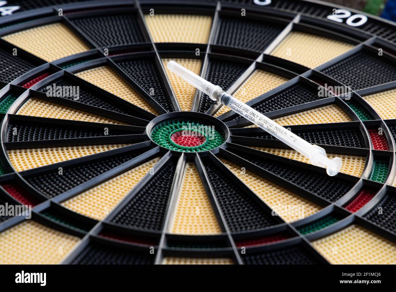 A closeup of dartboard with syringe in the red center, bulls eye. A ...