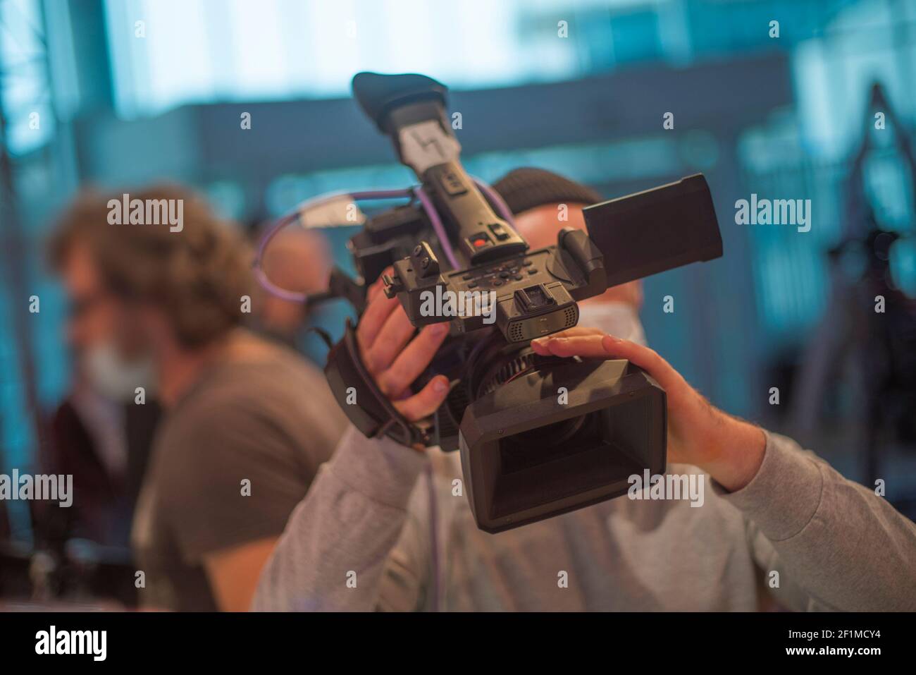masked cameraman is filming a television show in the studio. TV Stock ...