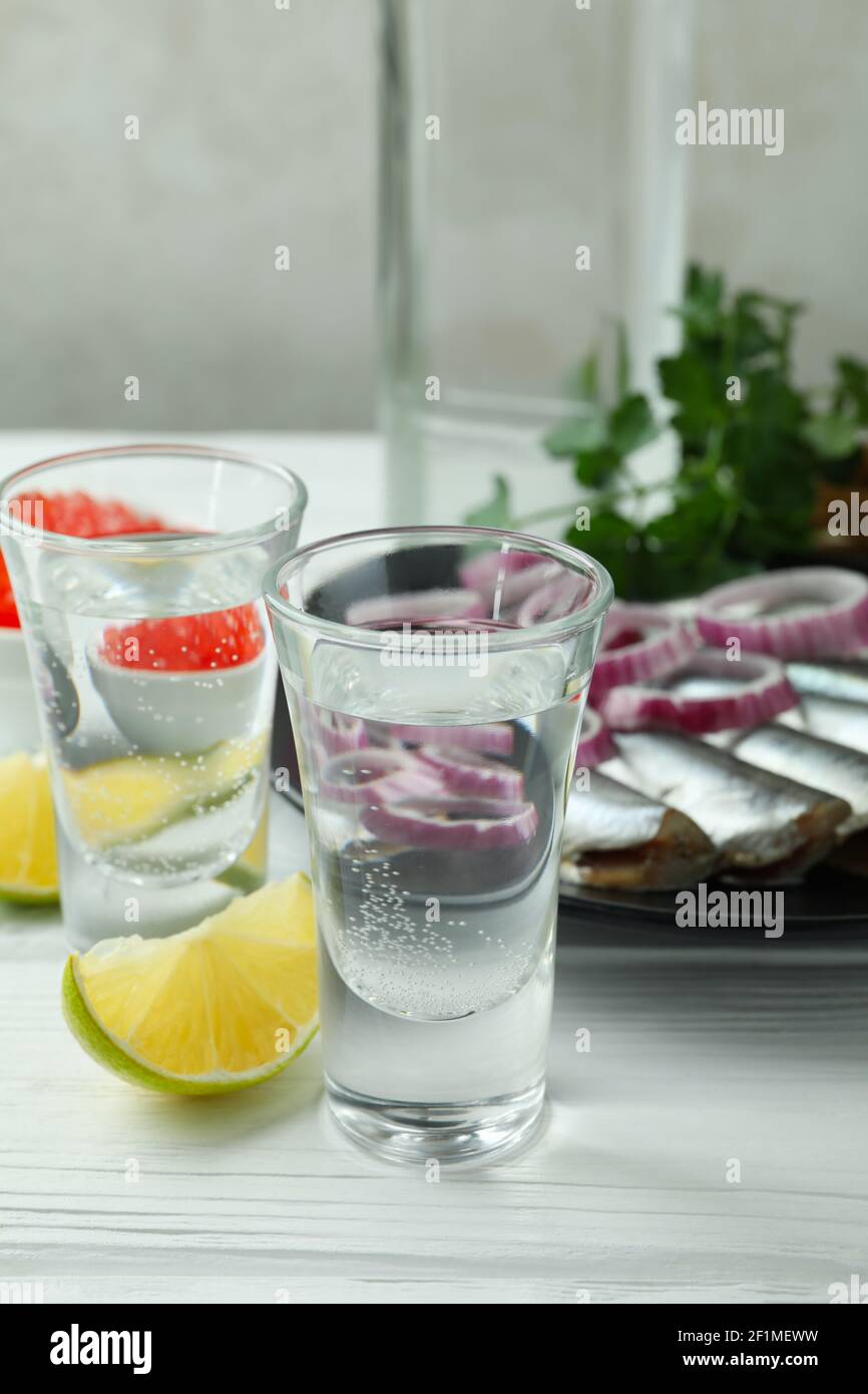 Shots of vodka and tasty snacks on white wooden background Stock Photo ...