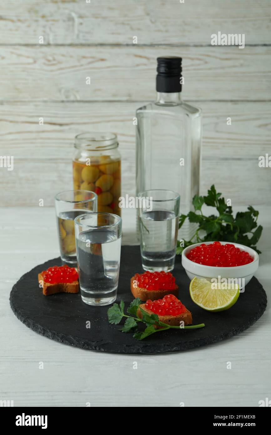 Shots of vodka and tasty snacks on white wooden background Stock Photo ...
