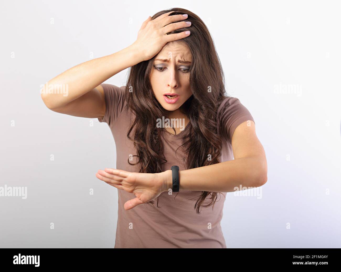Shocked young woman looking on the hand with wrist watch with unhappy ...