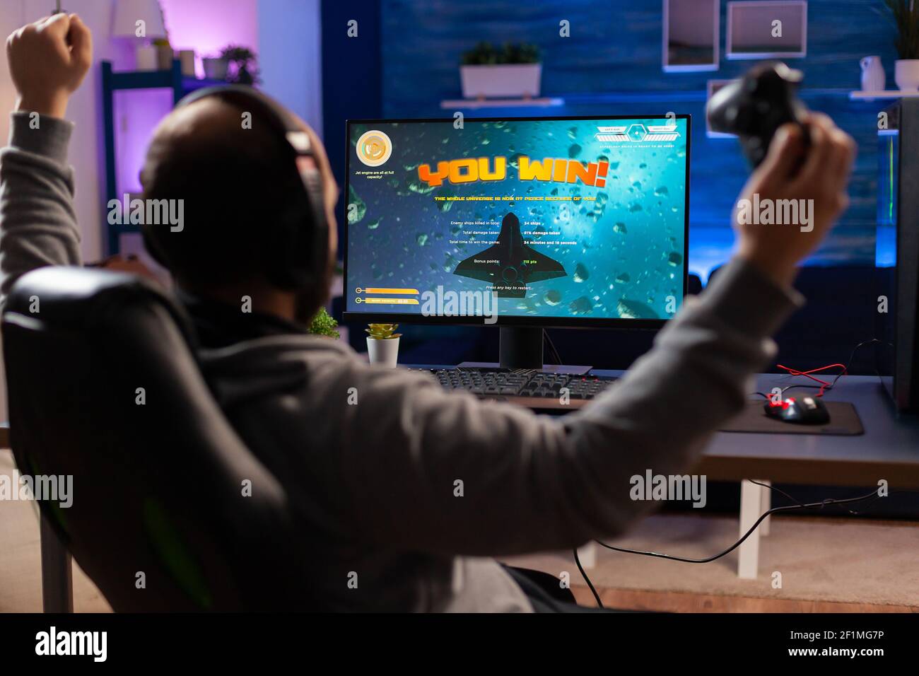 Addicted man playing space shooter videogame using headphones and ...