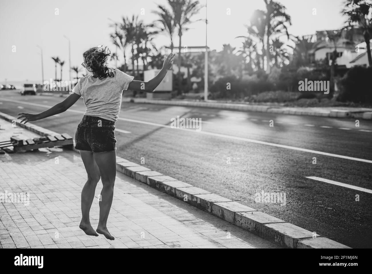 Black and white photo of a young girl in shorts in a jump in the summer ...
