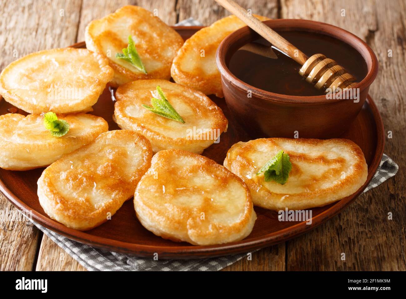 Authentic Tiganites Greek pancakes with honey close-up in a plate on ...