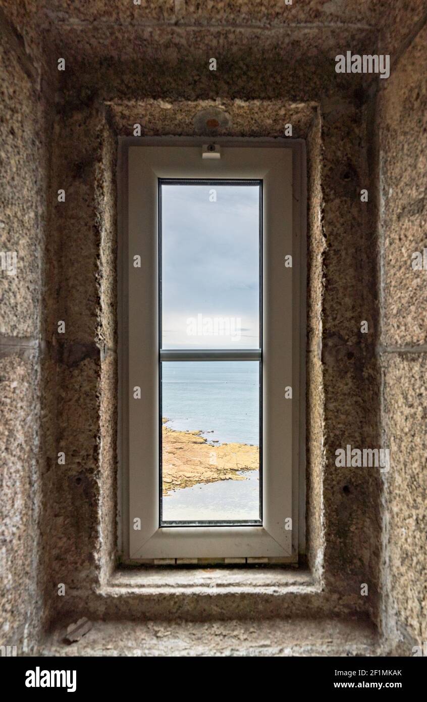 View of the ocean through a lighthouse window in the stone staircase ...