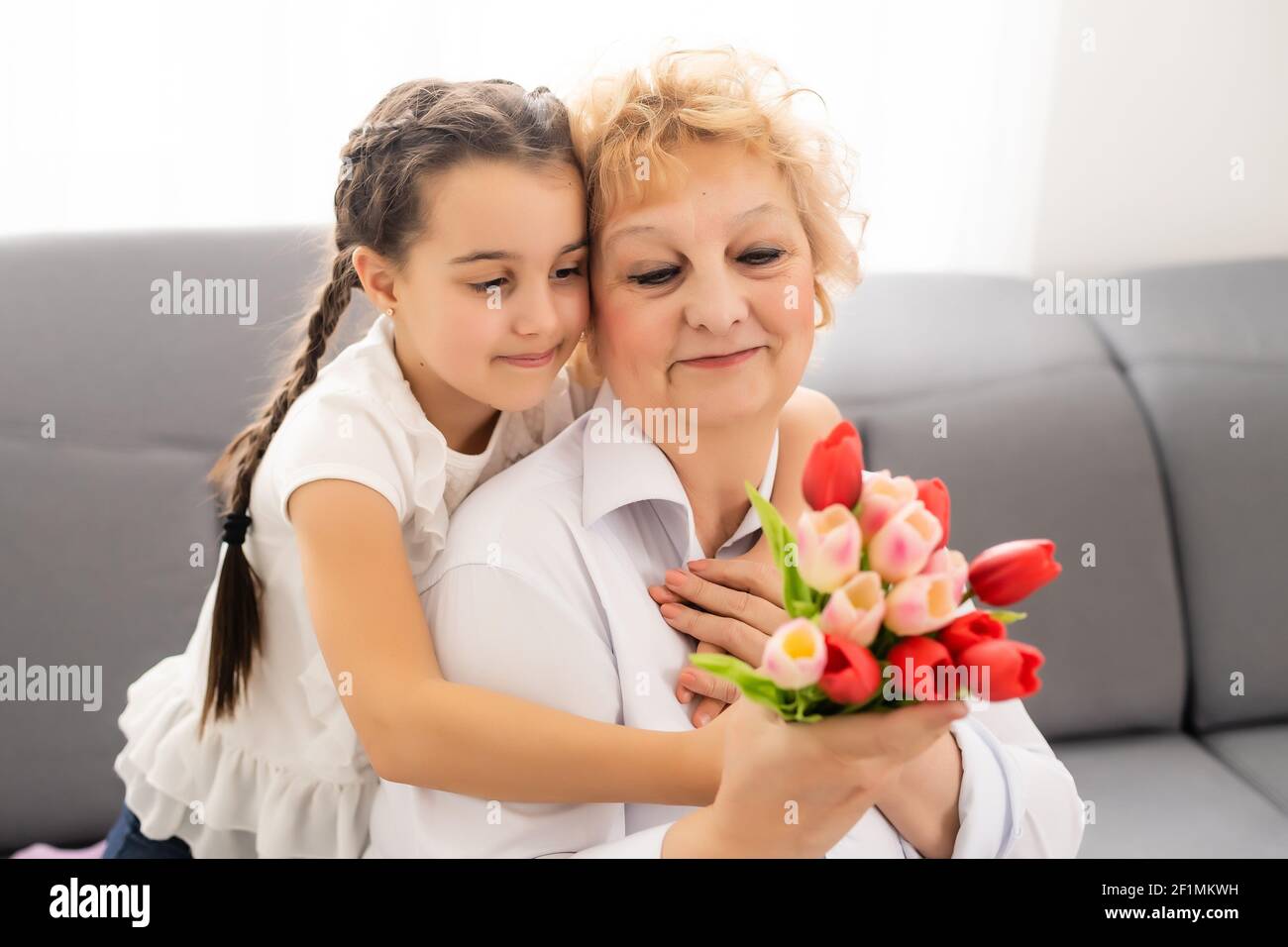Sincere cute little granddaughter strong cuddling and kissing in cheek ...
