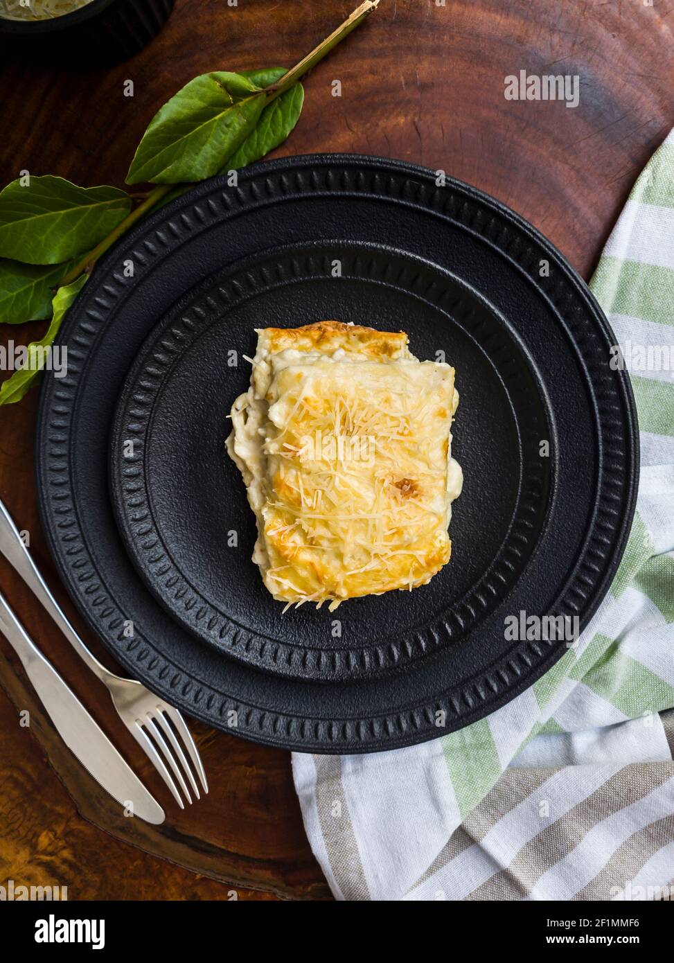 Delicious lasagna four cheeses on black ceramic plates, green leaves ...