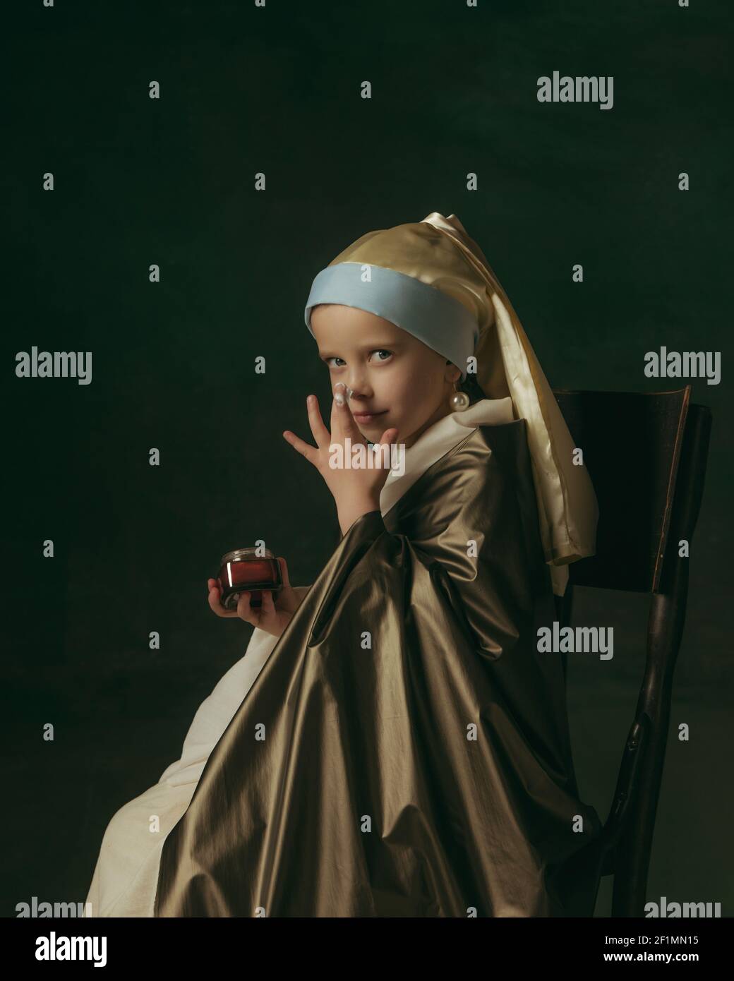 Using cosmetical face cream. Medieval little girl as lady with a pearl ...