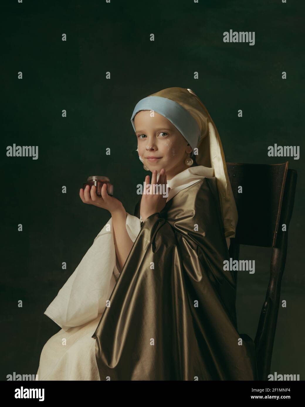 Using cosmetical face cream. Medieval little girl as lady with a pearl ...