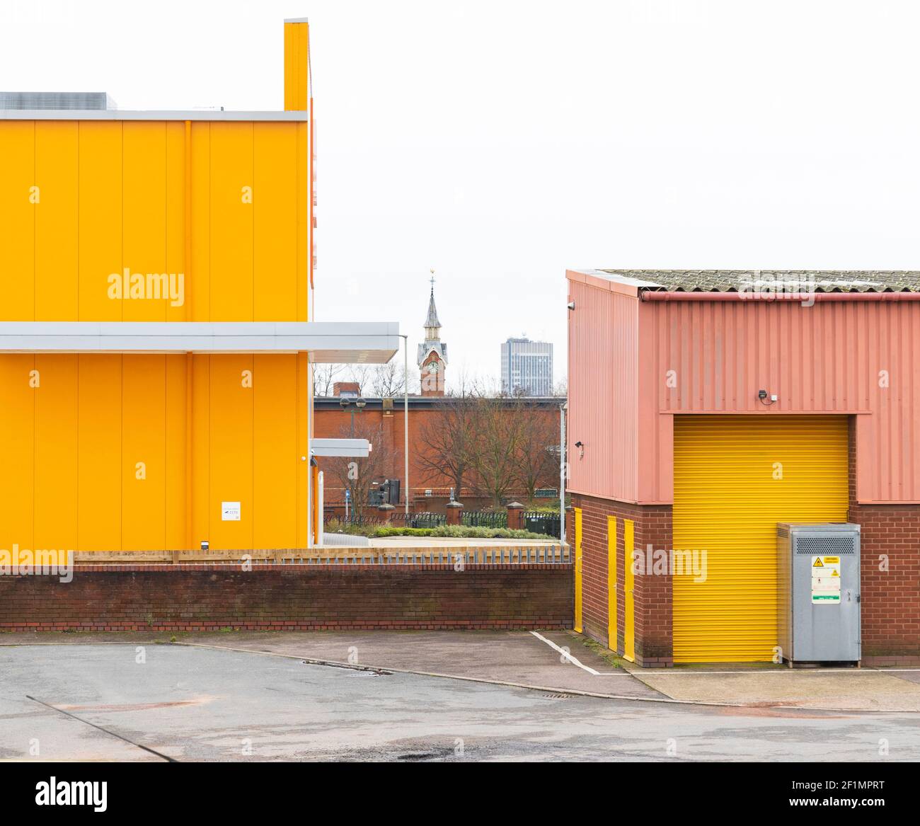 Bright yellow, pink corrugated warehouse units, brick wall. On the old ...