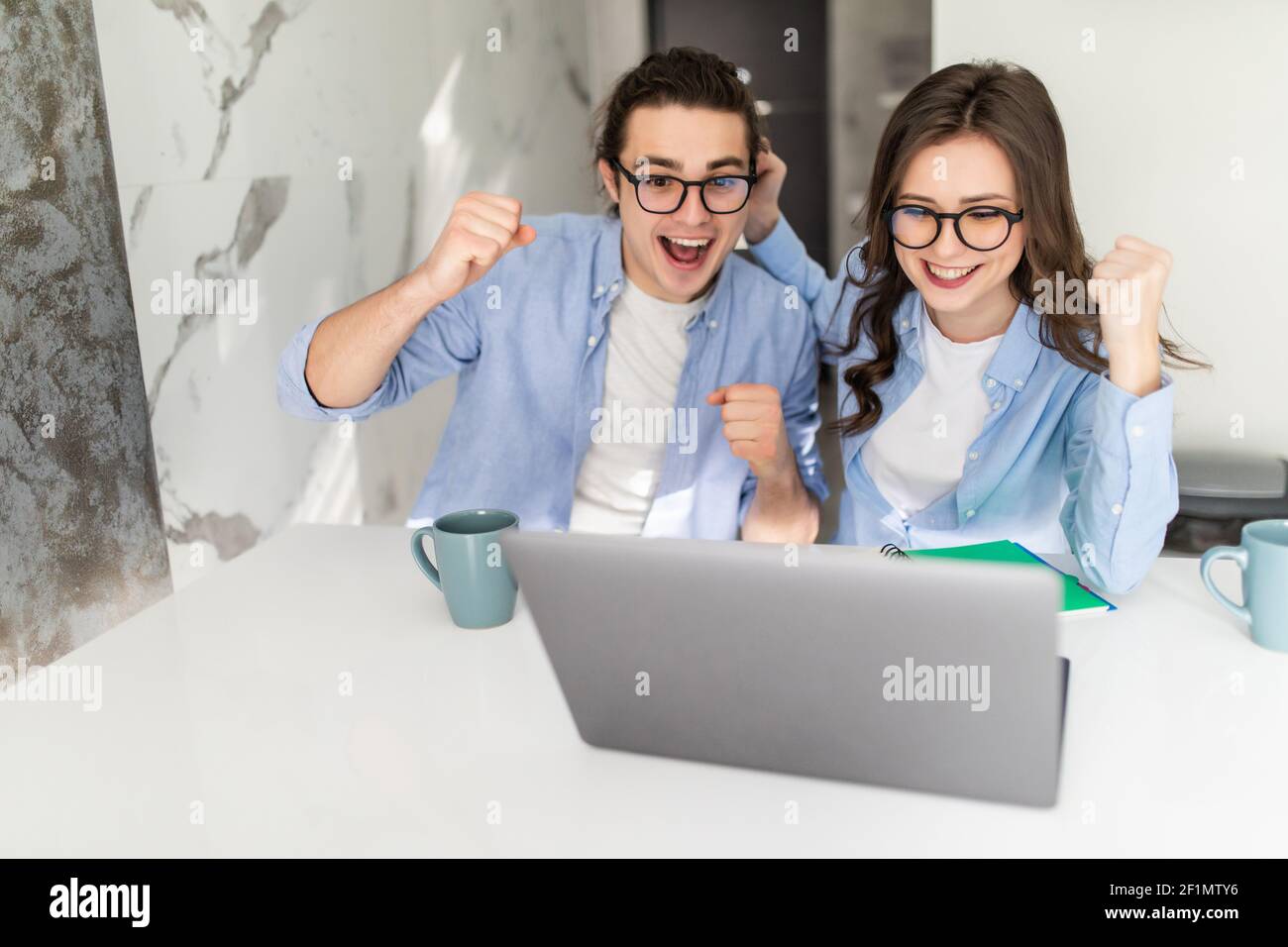 Young excited couple feeling ecstatic by online win looking at laptop ...