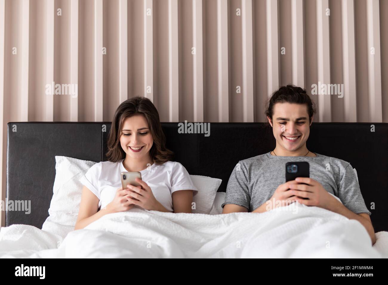 Angry couple everyone with their own phones lying on the bed at home ...