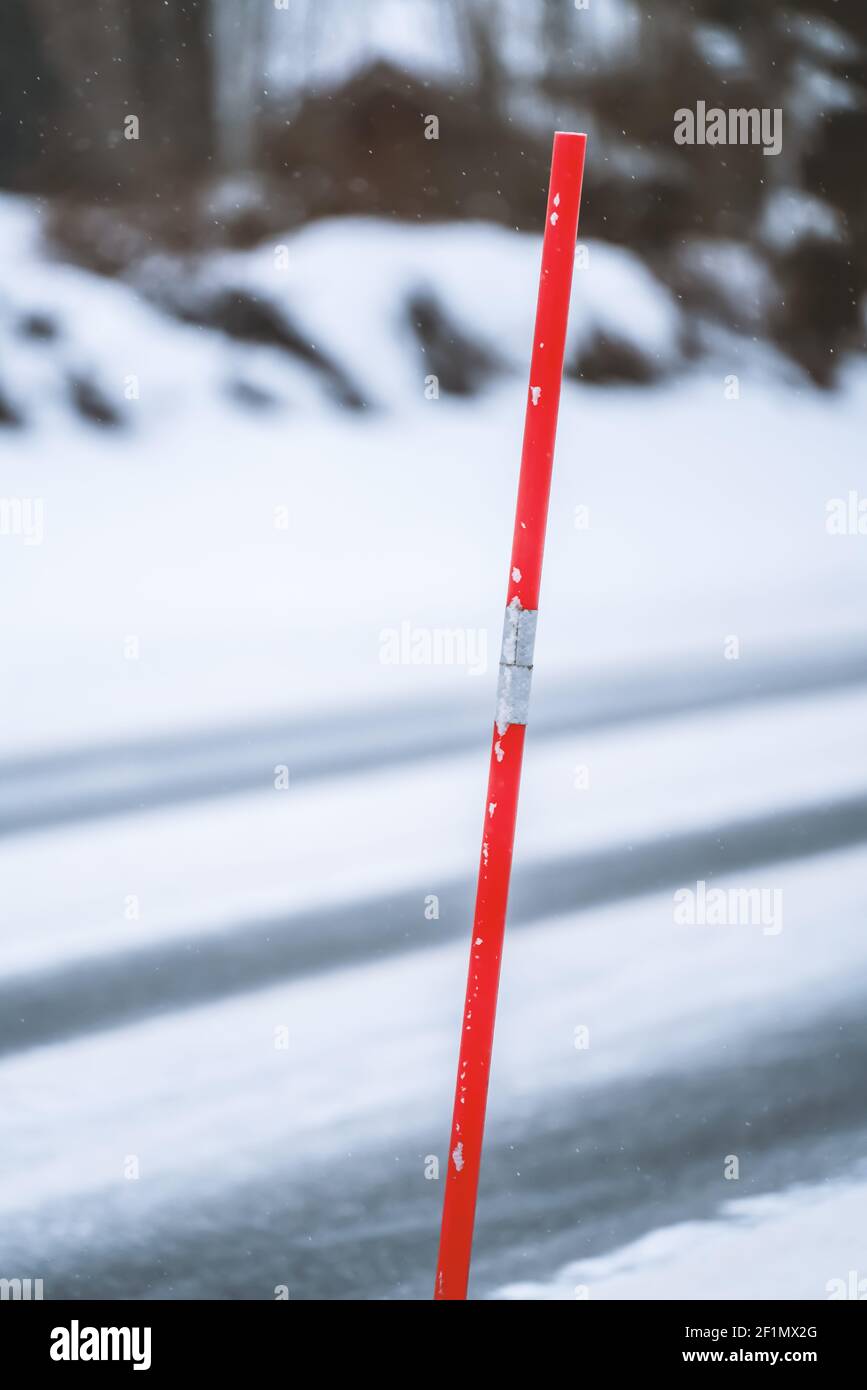 Road marking stick by the side of a road covered in snow and ice Stock ...