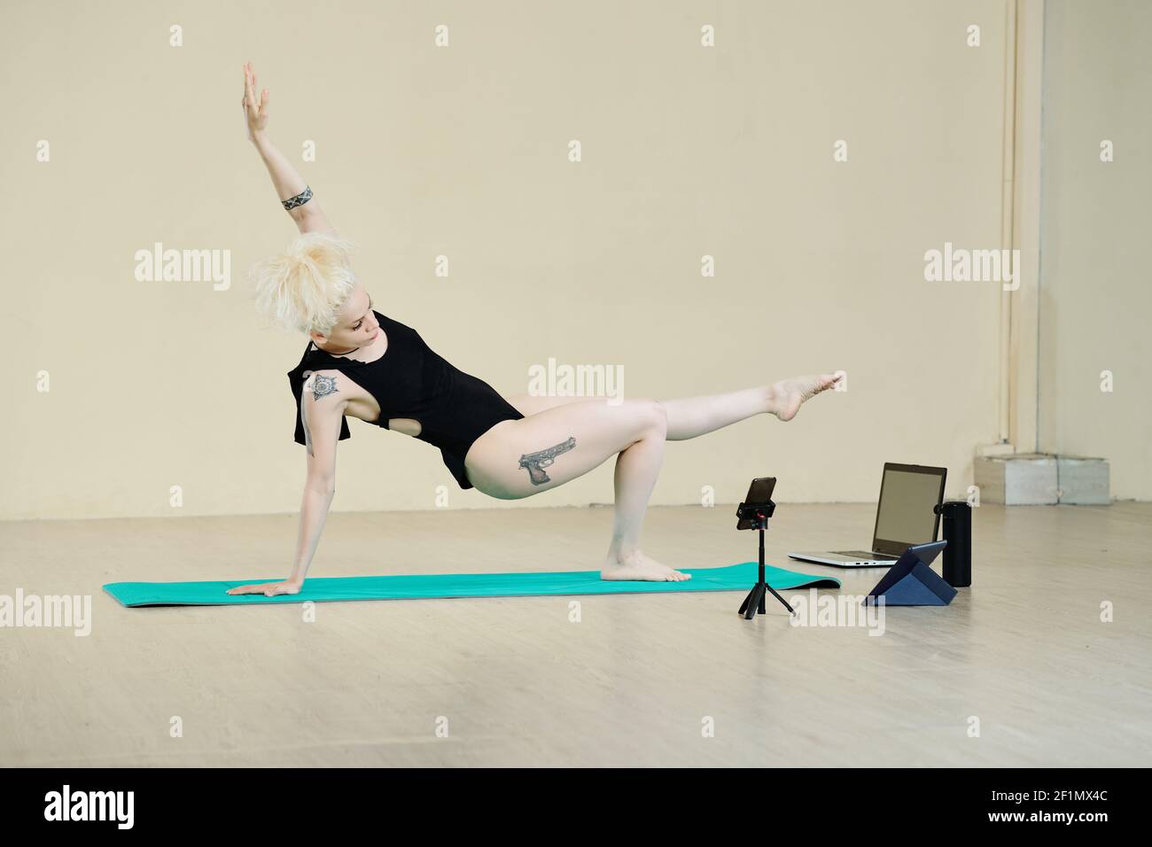 Beautiful fit young woman doing difficult balance exercise when filming ...