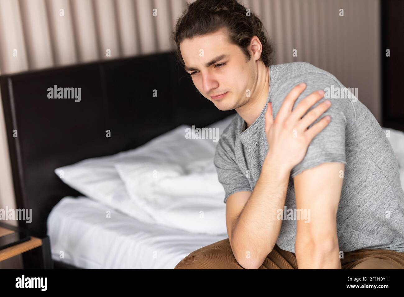 Man with upper arm pain.In the white bedroom there are boy. Guys are ...