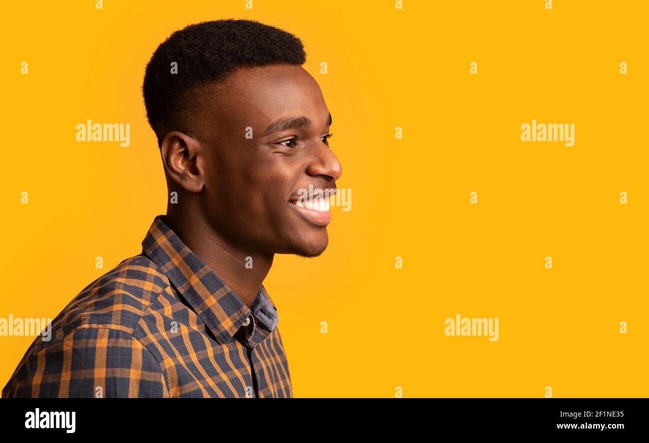 Side view shot of joyful millennial African American guy isolated over yellow background ...