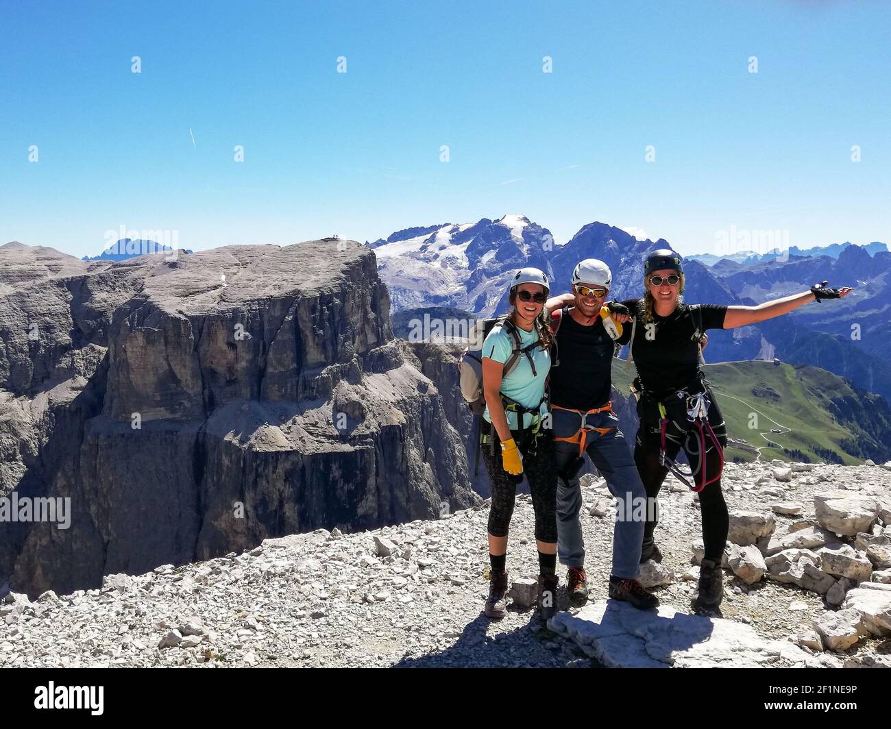 Mountain guide and two female climbers celebrate standing on the summit ...