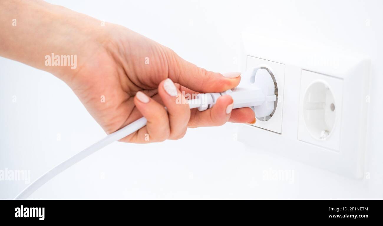 Hand plugging wire into socket on white wall Stock Photo - Alamy