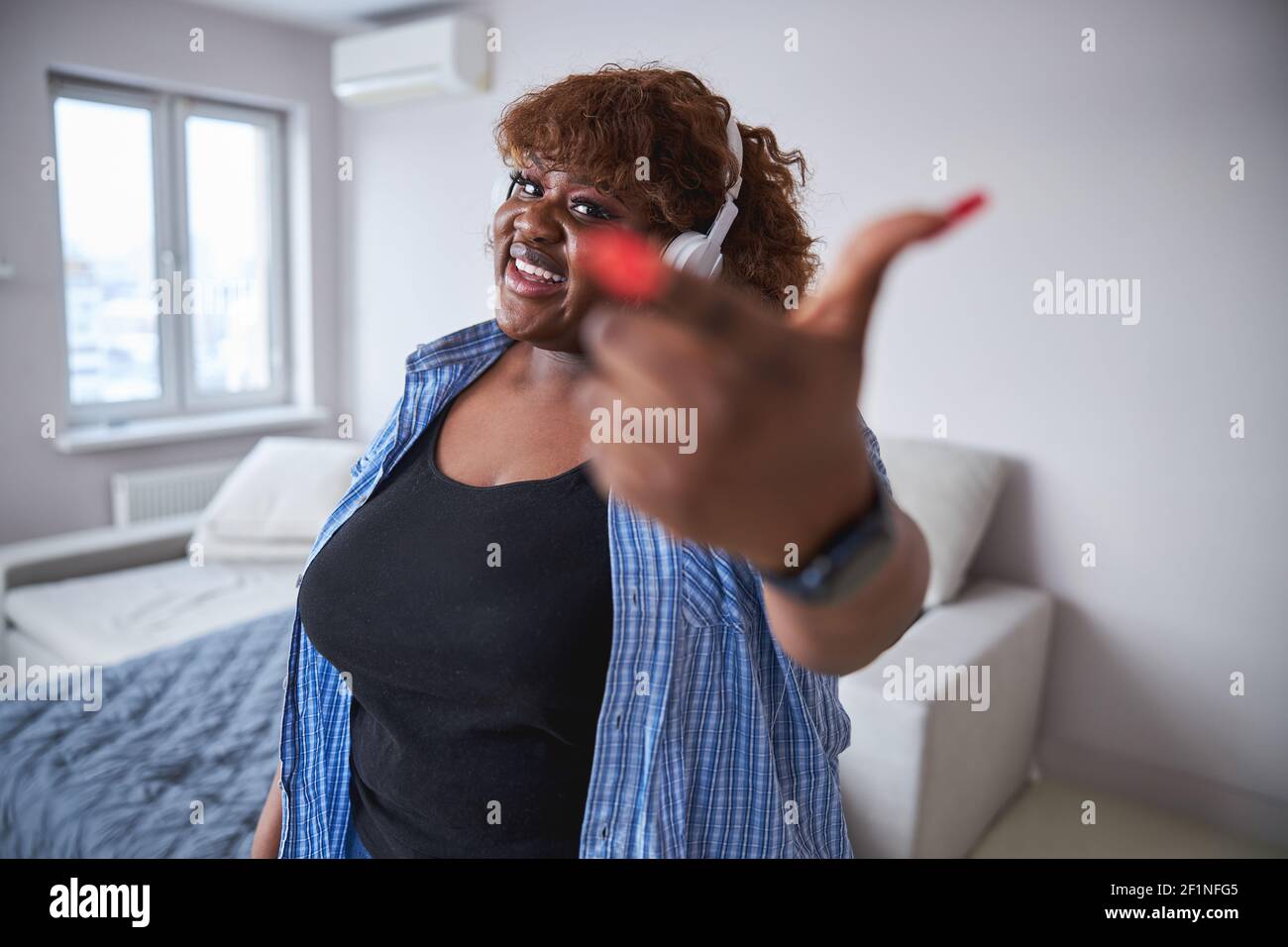 Active and smiley lady in headphones pointing at camera Stock Photo - Alamy