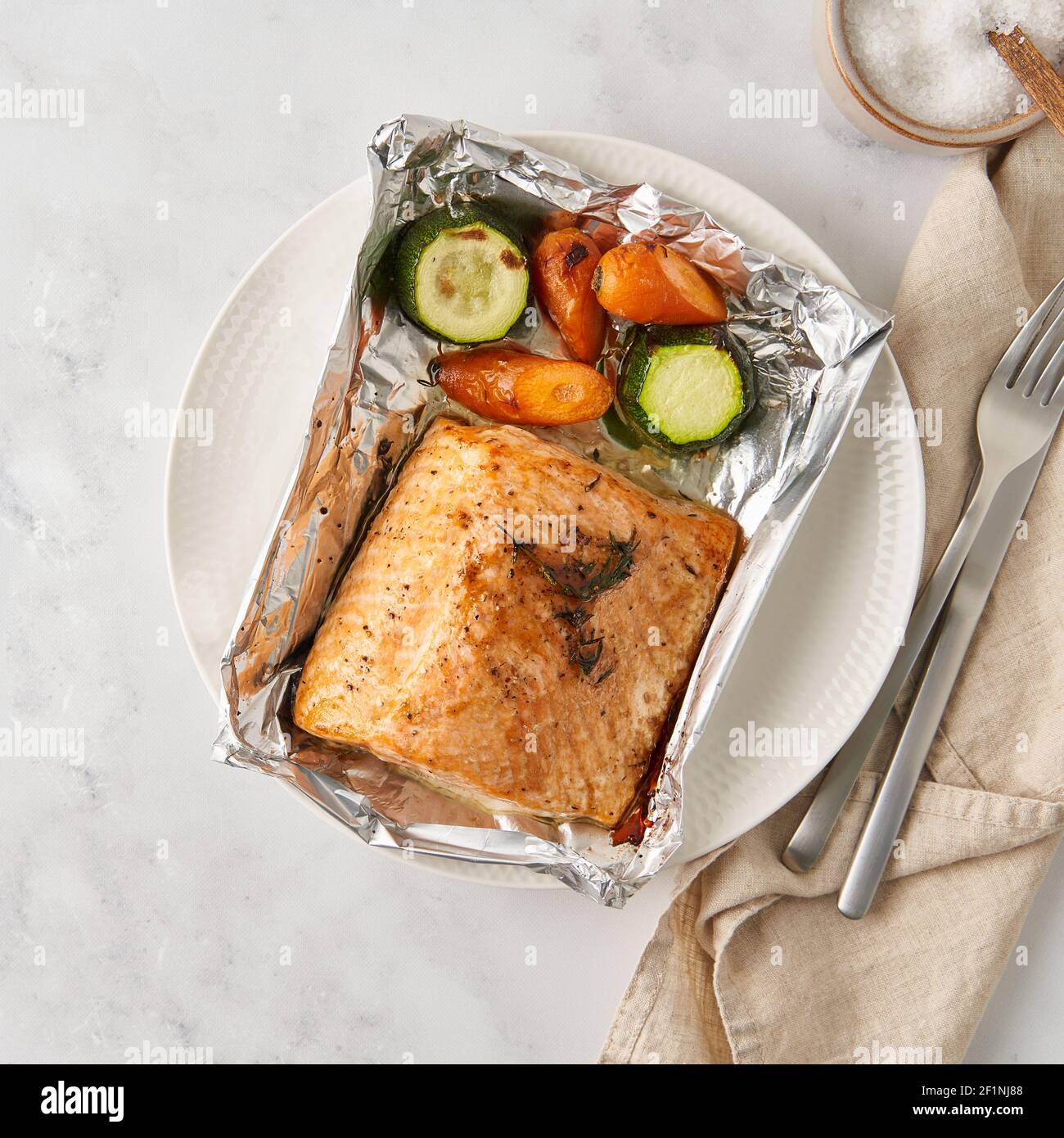 Foil pack dinner with fish. Fillet of salmon with vegetables on white ...