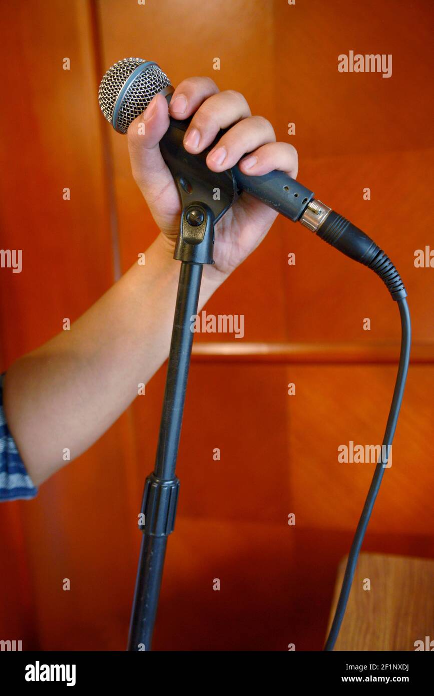Man hand holding microphone with wall background Stock Photo - Alamy