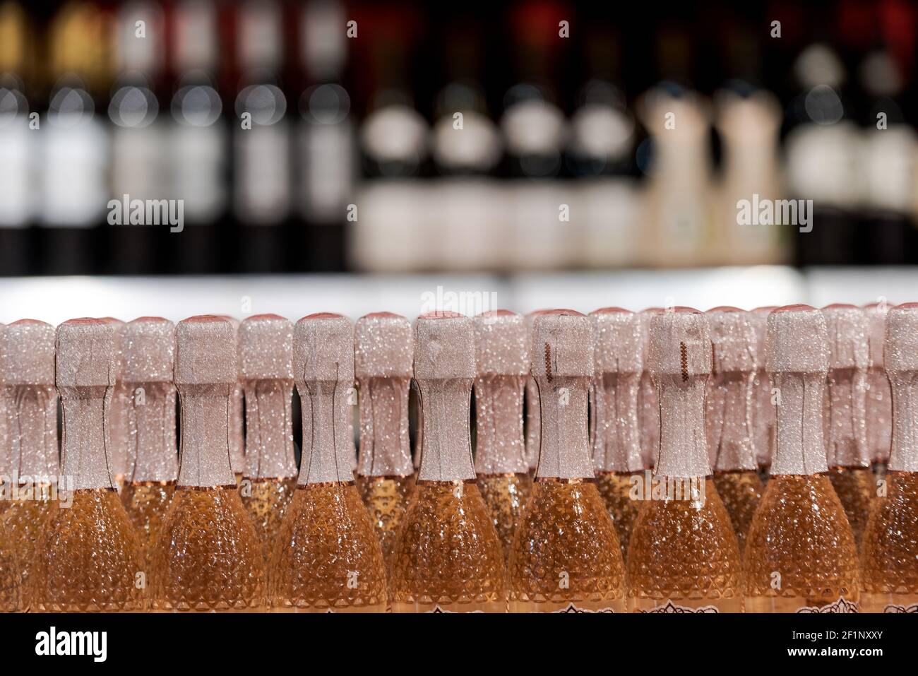 Row of fancy bottles of sparkling wine in supermarket with blurred wine ...
