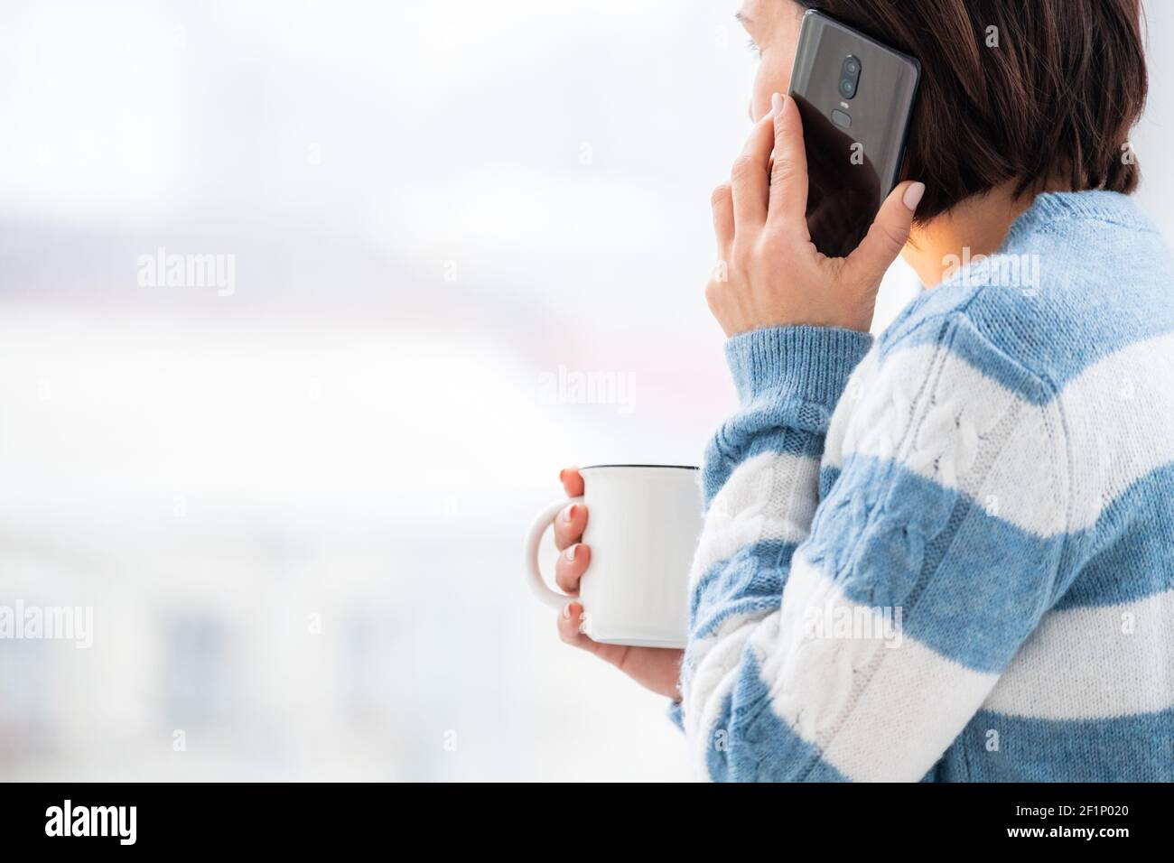 Girl talking on phone while drinking from cup Stock Photo - Alamy