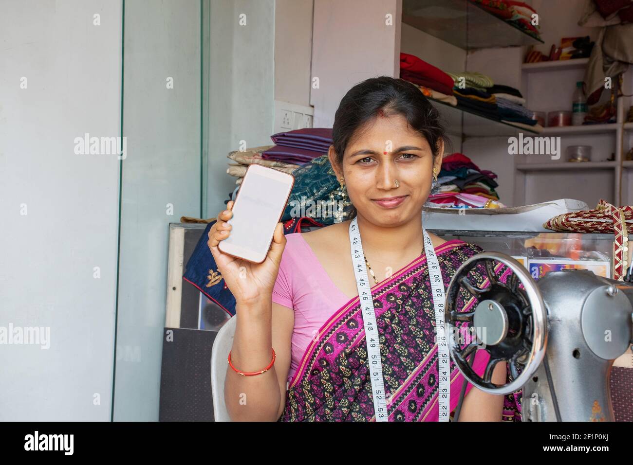 Indian woman textile worker showing mobile phone at workshop Stock ...
