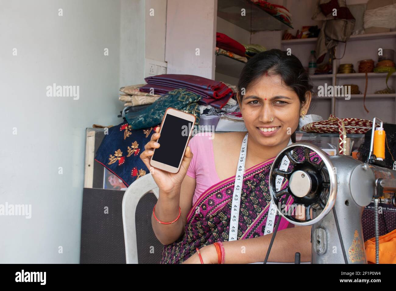 Indian woman textile worker showing mobile phone at workshop Stock ...