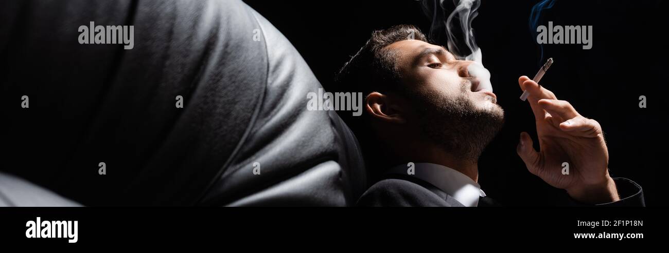 Man in suit smoking cigarette on couch isolated on black, banner Stock ...