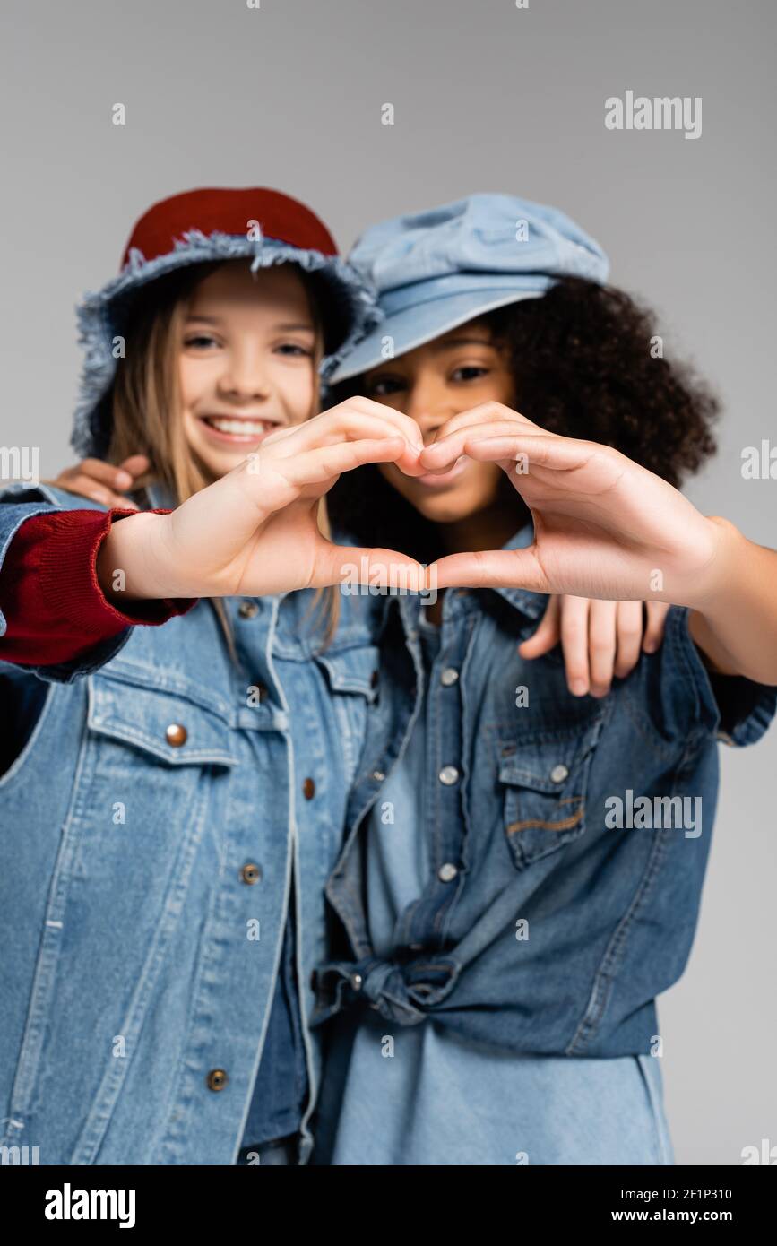 happy multicultural girls in stylish clothes showing heart symbol with ...