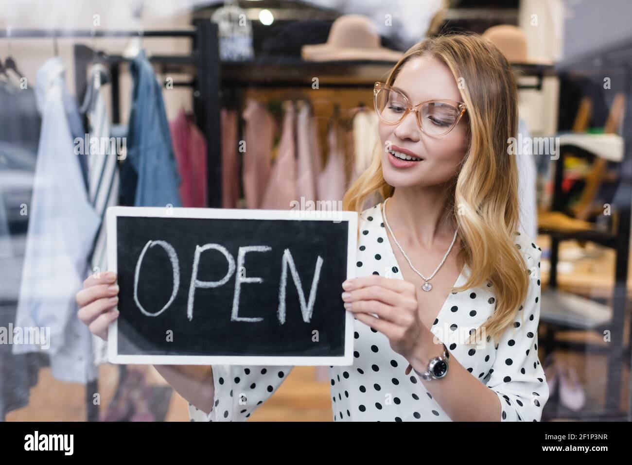 smiling proprietor holding board with open lettering in fashion ...