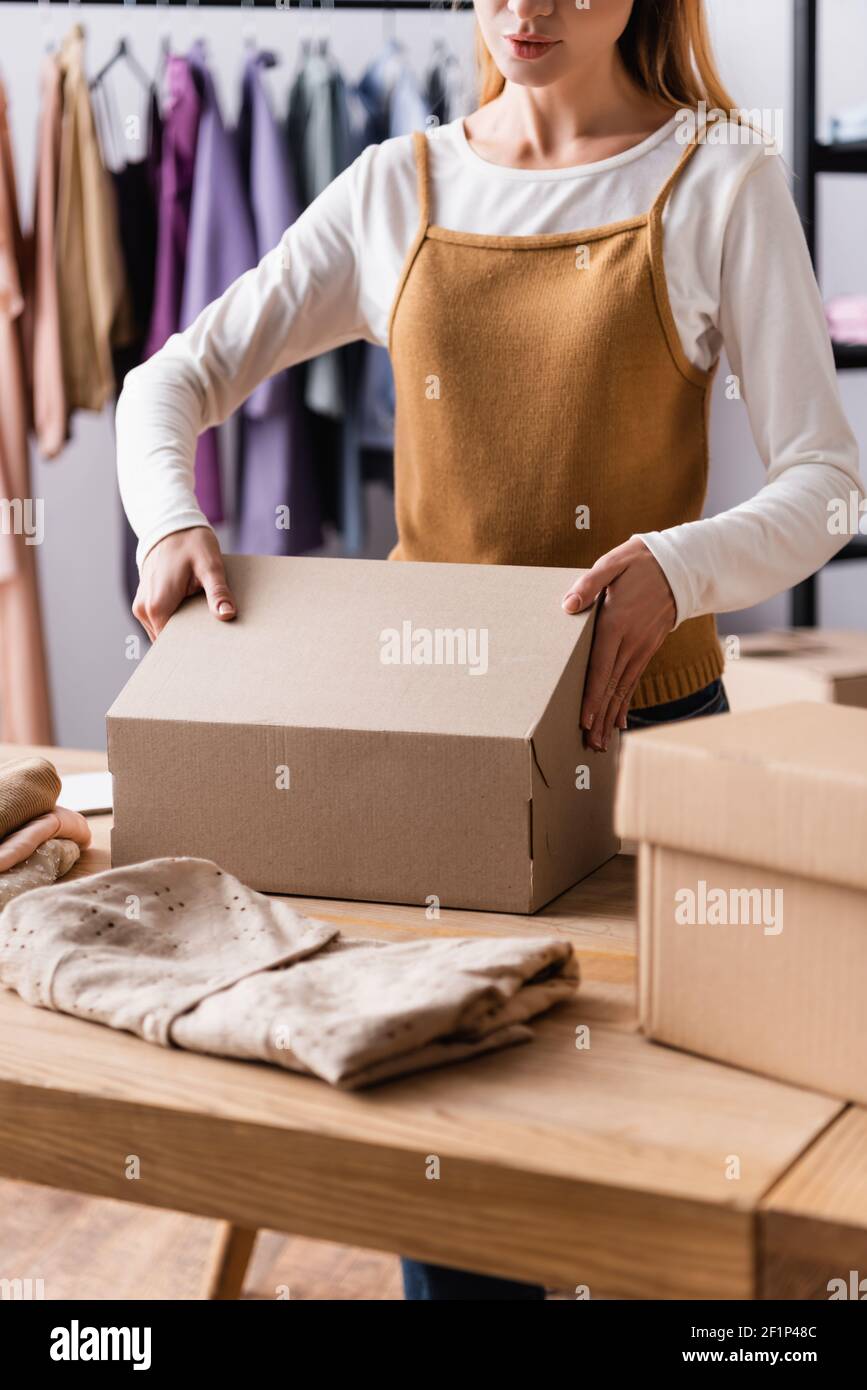 partial view of seller packing carton boxes in clothes showroom ...
