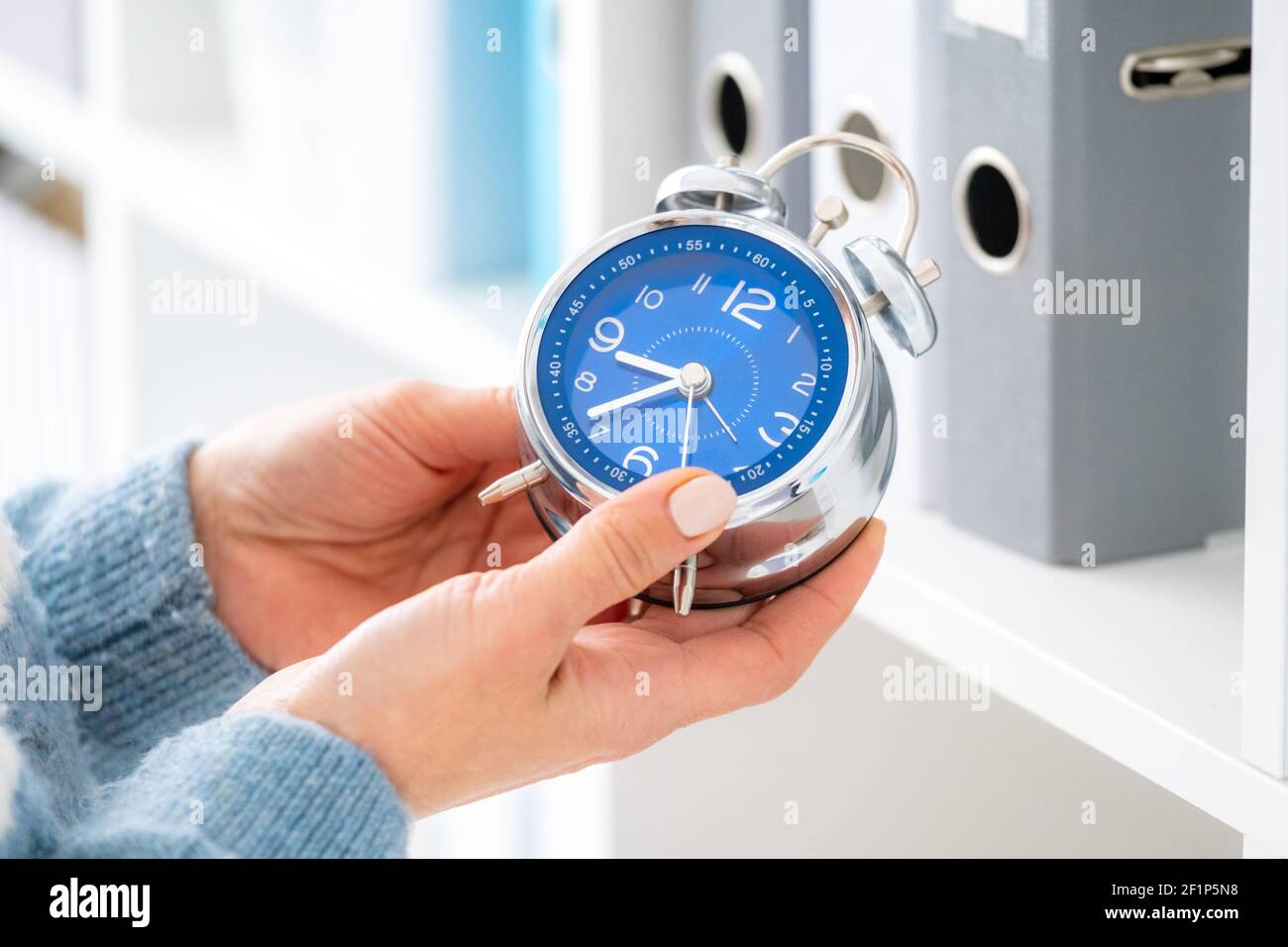 alarm clock in female hands in office Stock Photo - Alamy