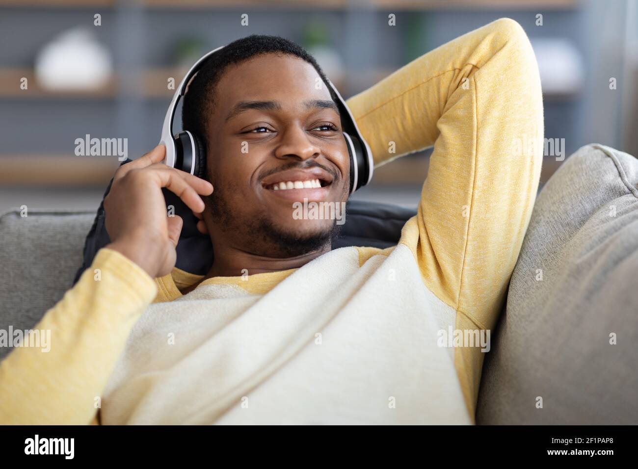 Closeup portrait of happy black guy in wireless headset reclining on ...